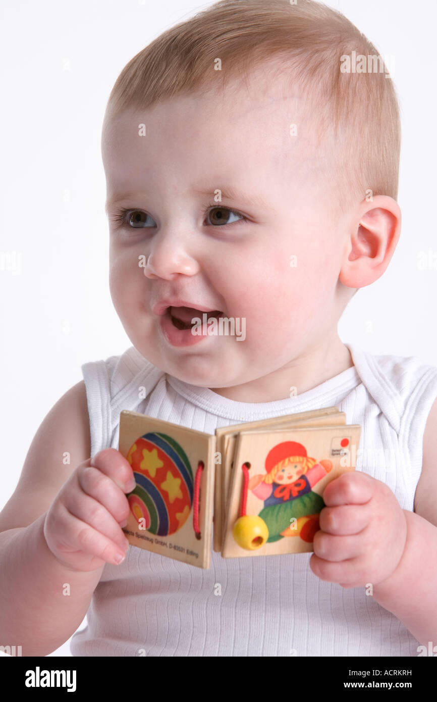 Baby boy with a wooden toy book Stock Photo - Alamy
