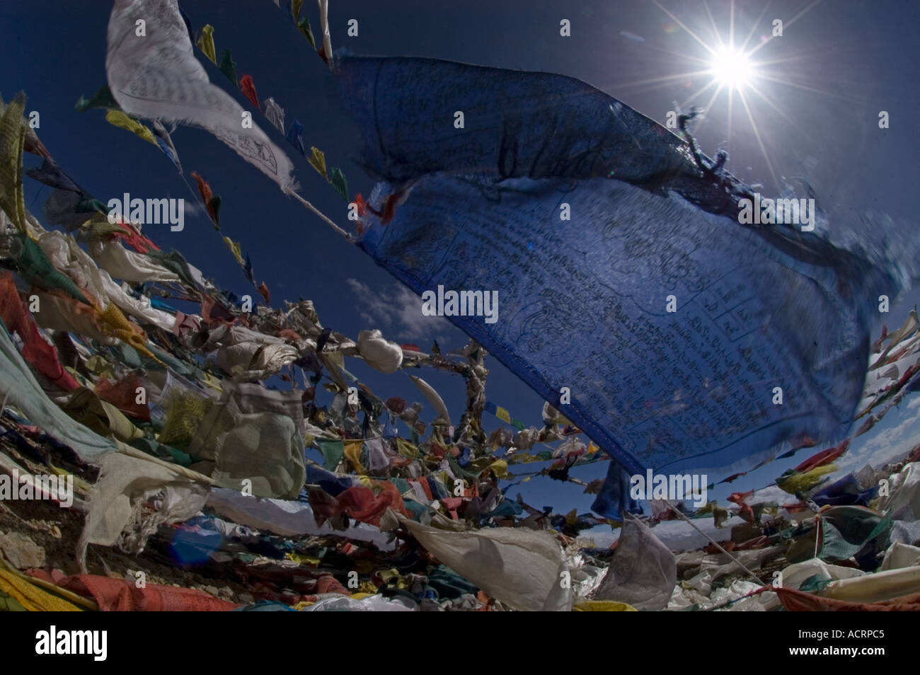 Prayer flags flutter under a Tibetan sun atop the Tsong La Pass, Tibet ...