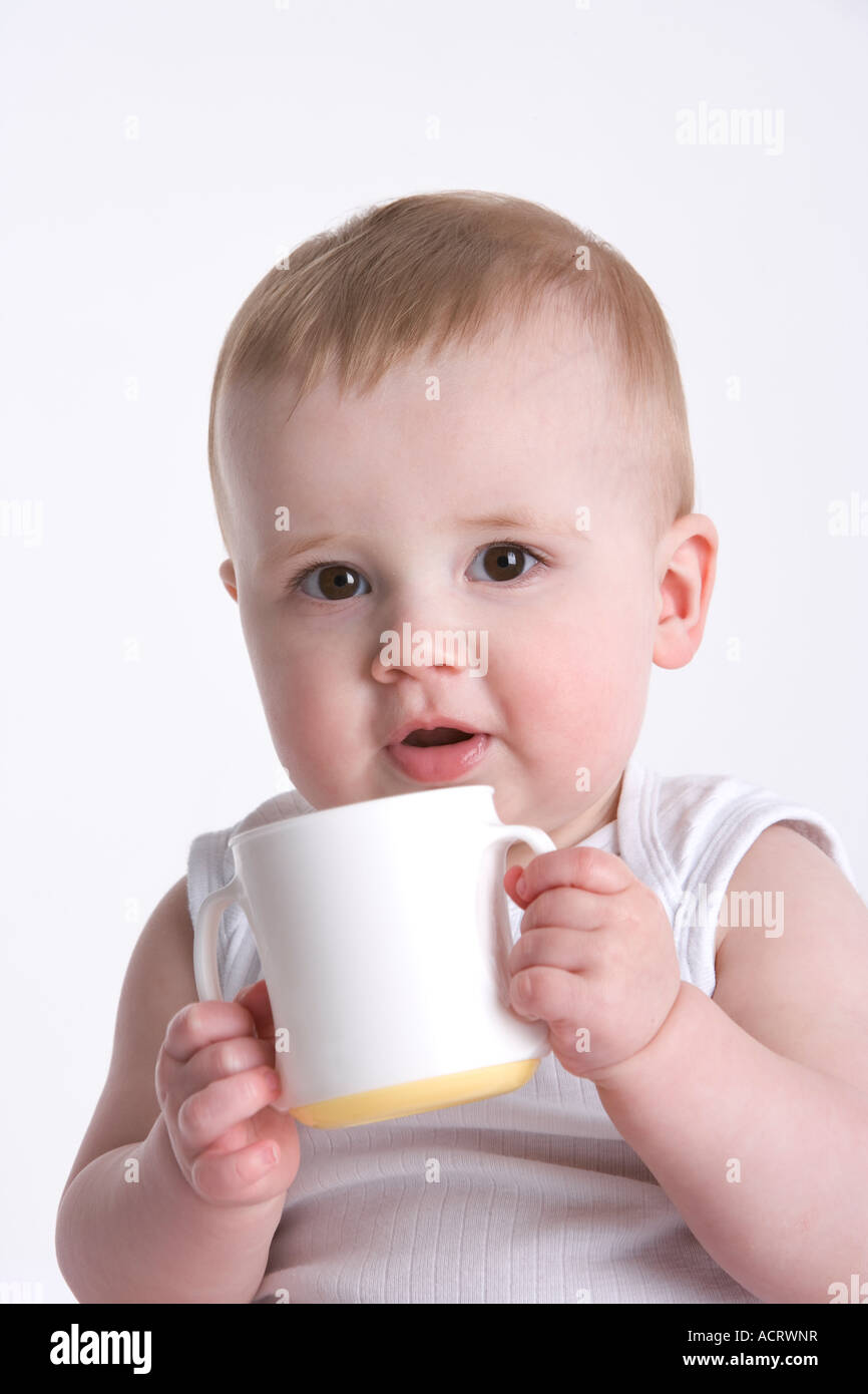Baby boy holding a white a baby cup Stock Photo - Alamy