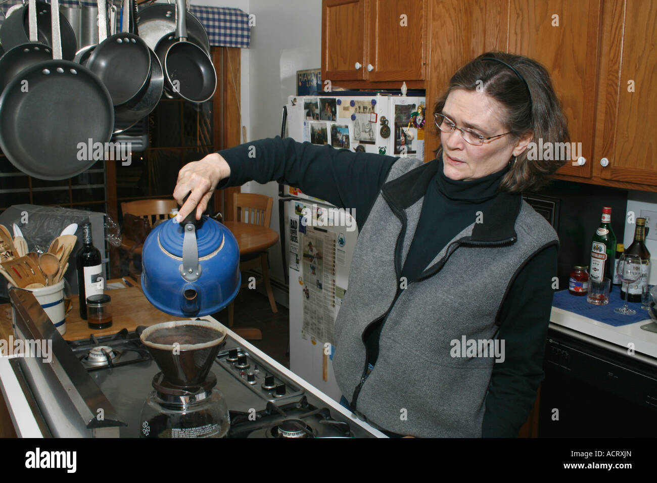 Mature woman age 59 pouring hot water into a coffee making funnel. "St ...