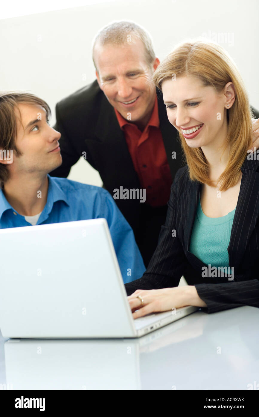 Three workers talk while using a laptop Stock Photo - Alamy