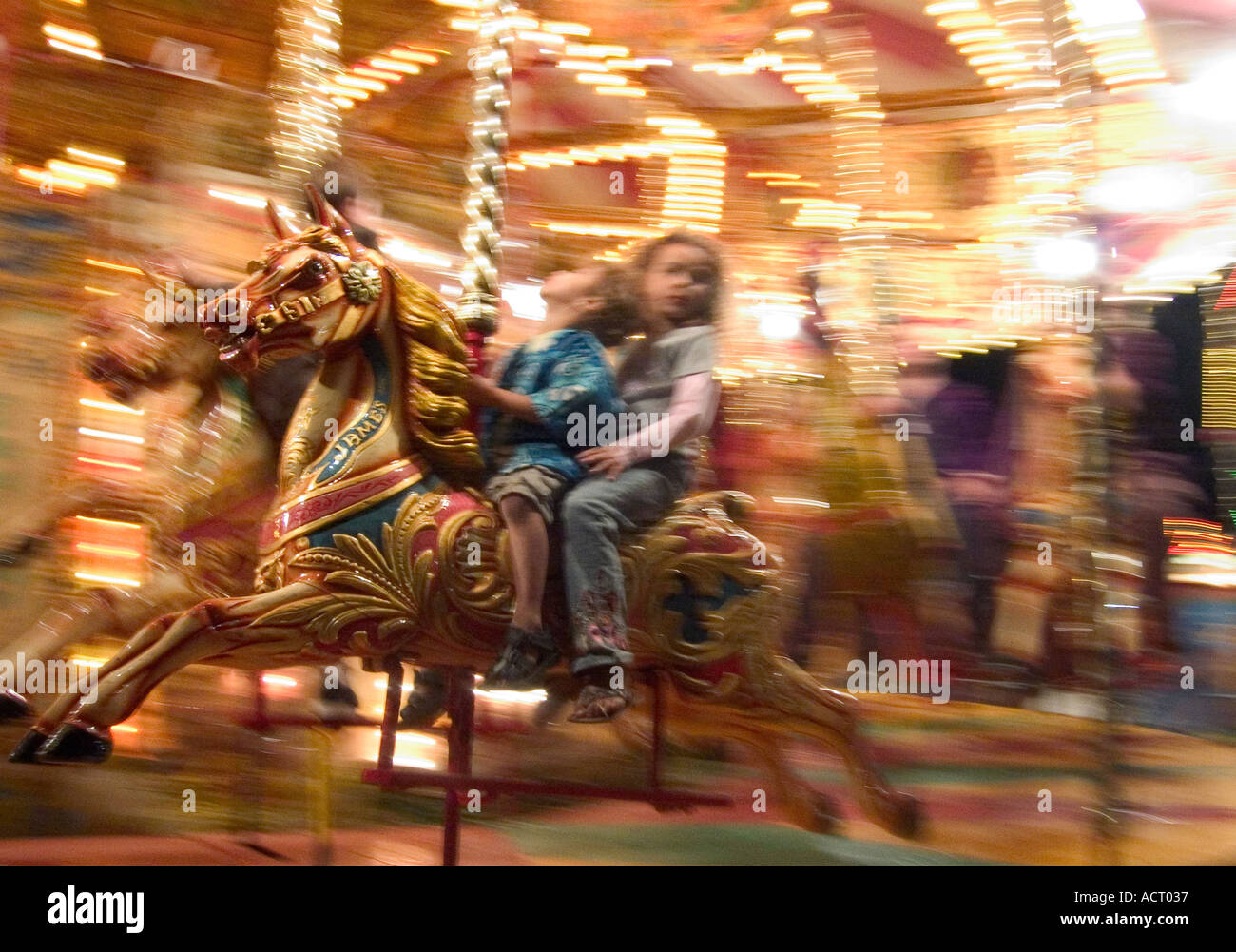 two children boy and girl on fairground gallopers ride - panned shot ...