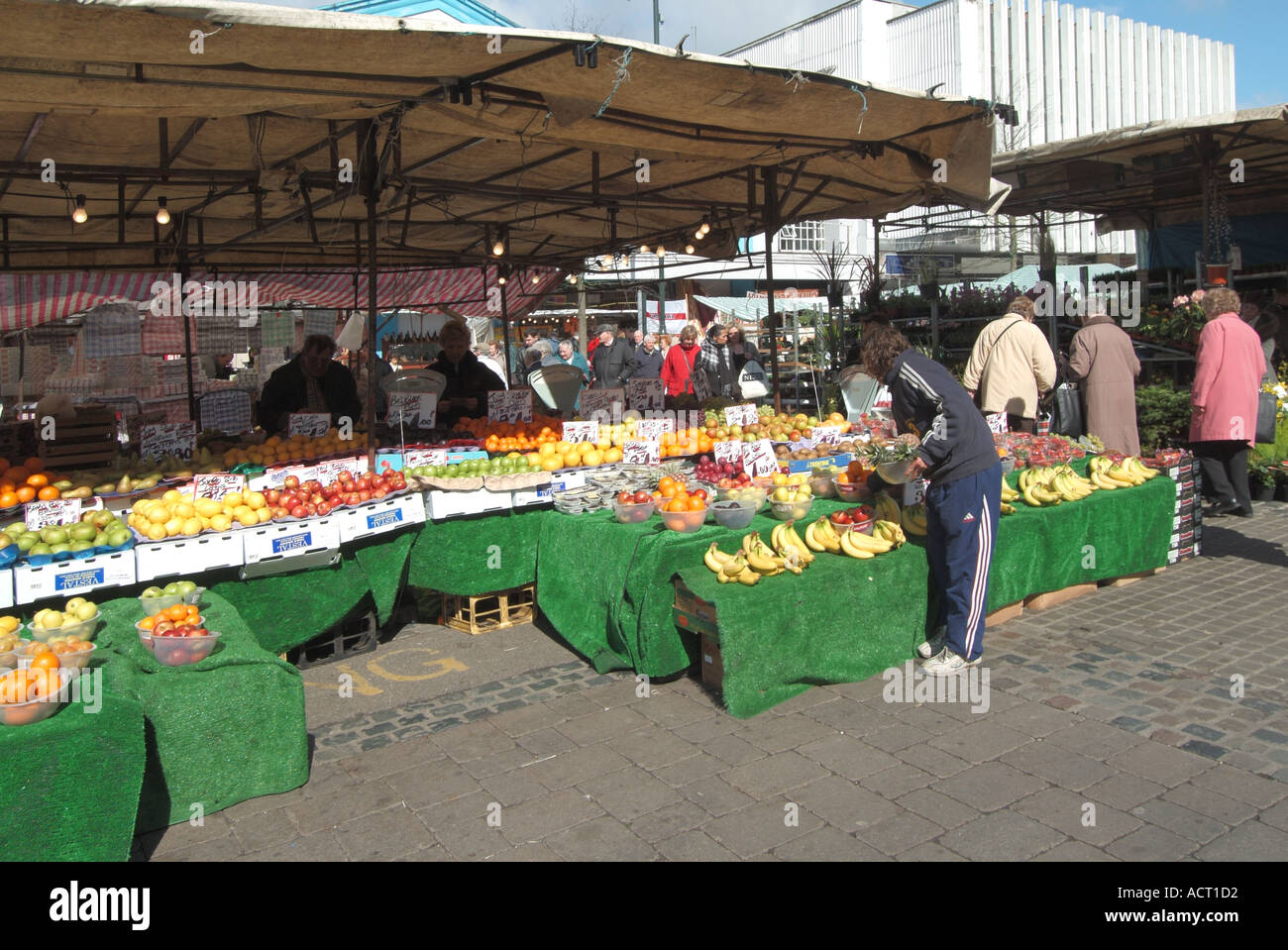 East London market trader working fruit and vegetables displayed on ...