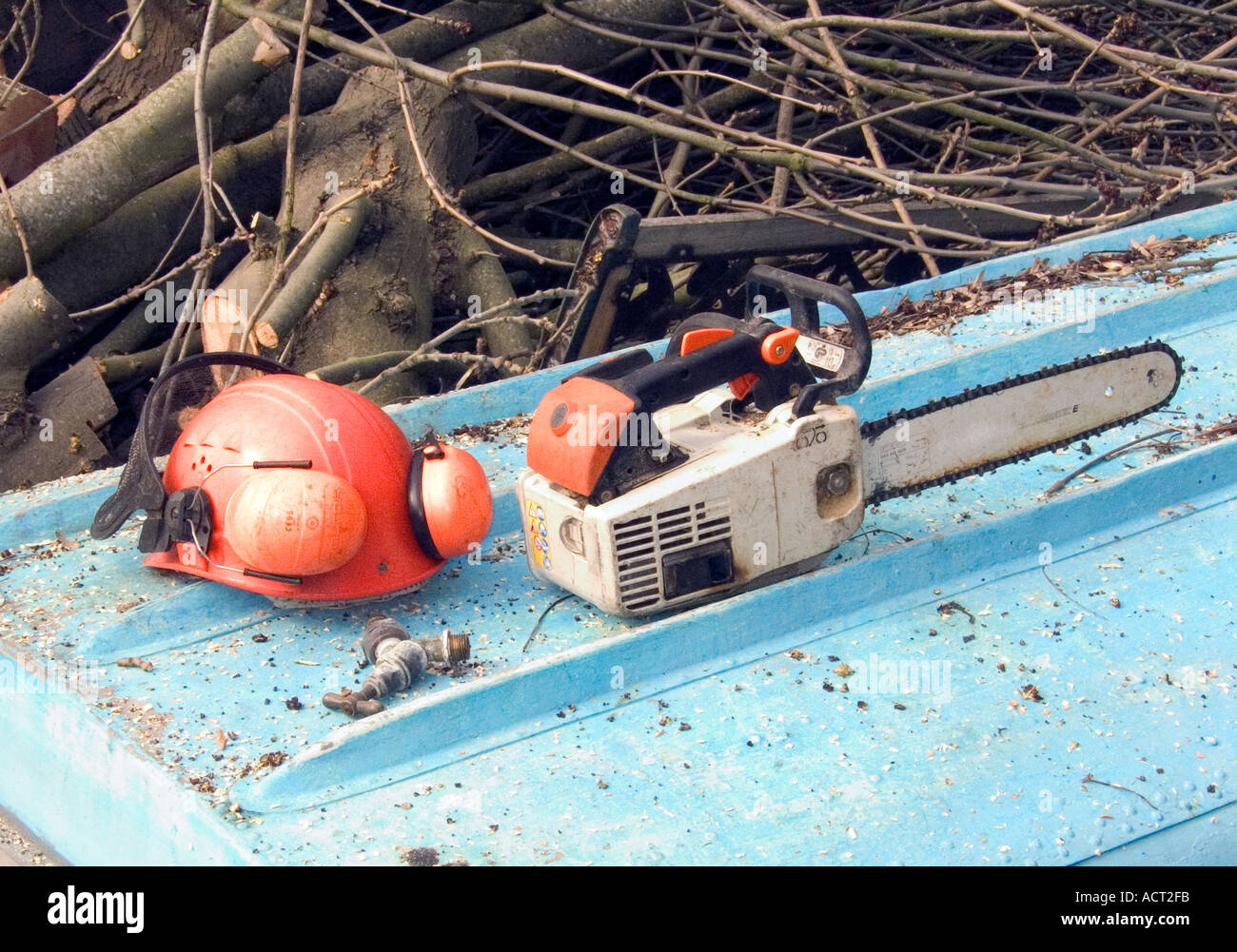 tree surgeons safety helmet and chainsaw next to a pile of branches ...