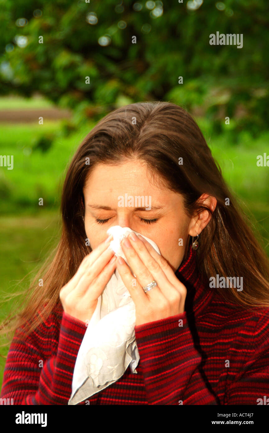Woman sneezing into handkerchief in garden Stock Photo - Alamy