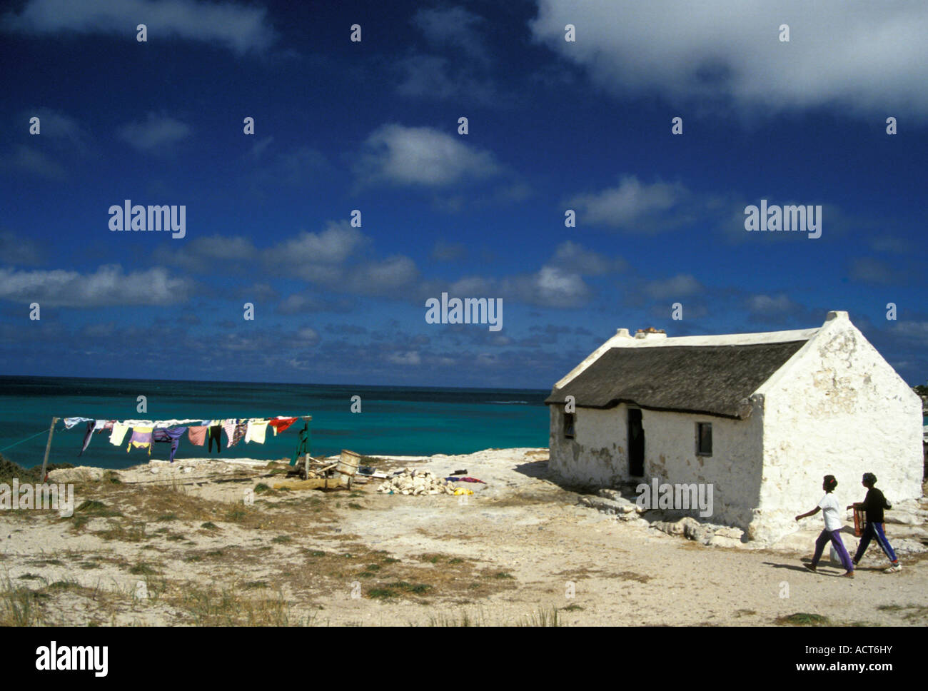 A stark white cottage overlooking the ocean with a makeshift washing ...