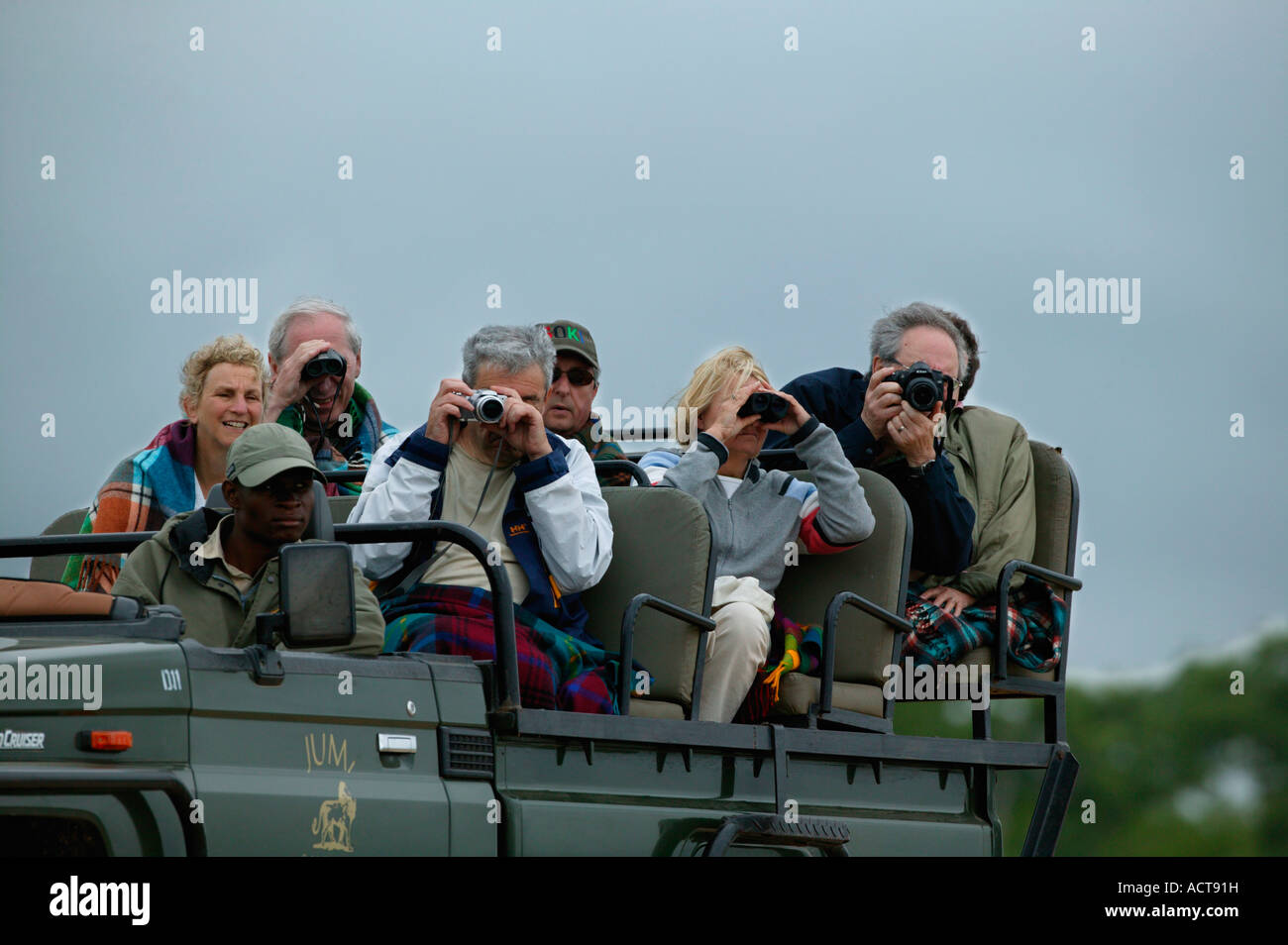 Tourists viewing and photographing game from open game viewing vehicle ...