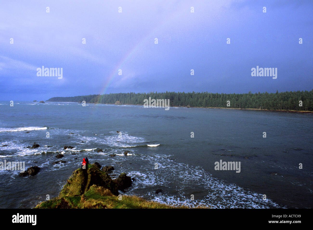 Hiker and rainbow at Sand Point, Lake Ozette Area of Olympic National ...
