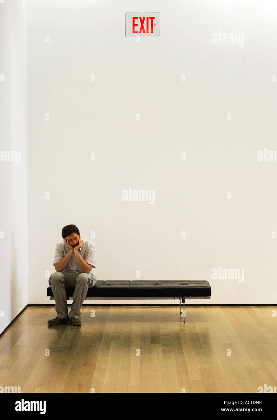 man resting on bench near exit sign Stock Photo - Alamy