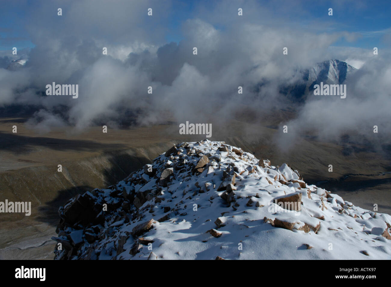 Fresh snow on rock with clouds sun and shadow on mountains and steppe ...