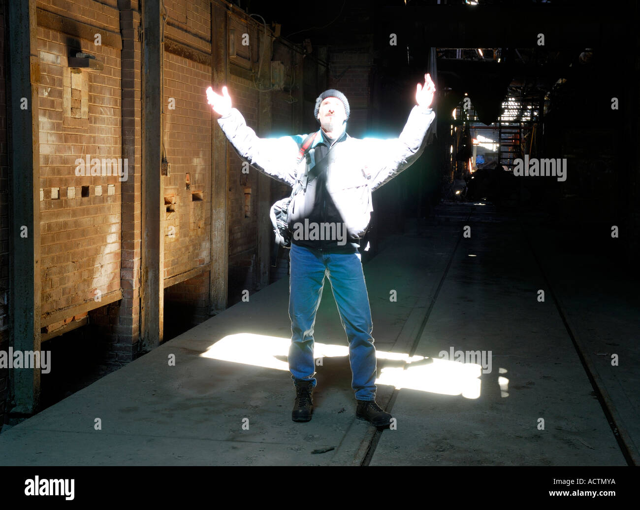 Male urban explorer reaching up to the light in the abandoned ...