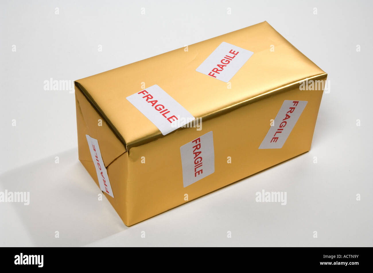 A parcel wrapped in gold paper marked with Fragile stickers Stock Photo ...