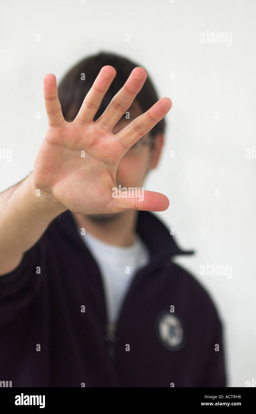 Young man holding hand up in front of face Stock Photo - Alamy