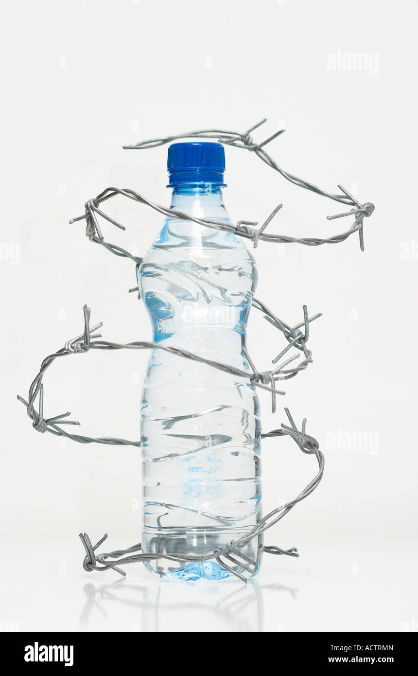 Bottle of water surrounded by barbed wire close up Stock Photo - Alamy