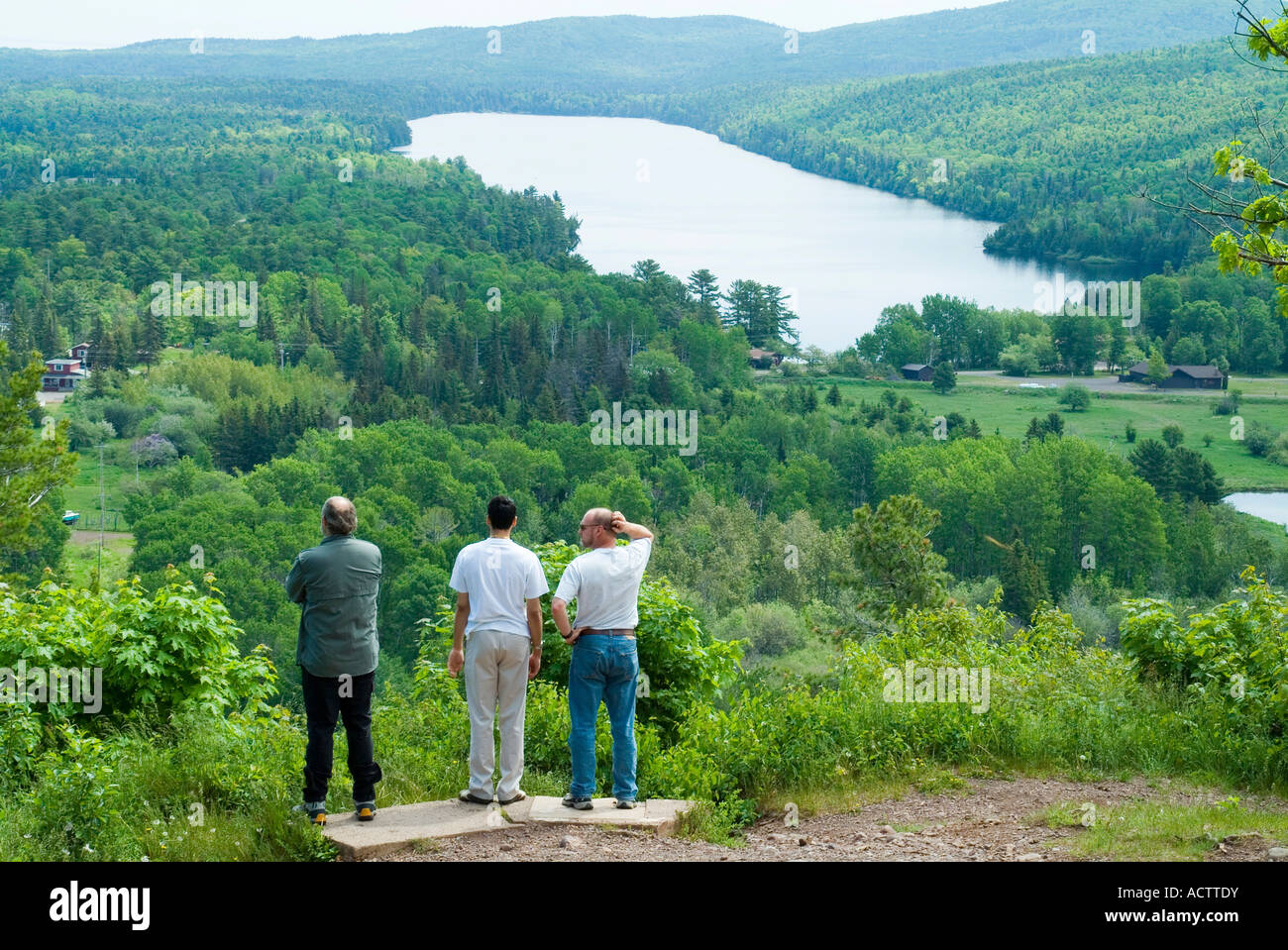 A GROUP OF THREE MEN LOOKING OUT TO THE BEAUTIFUL NATURAL SCENERY OF ...