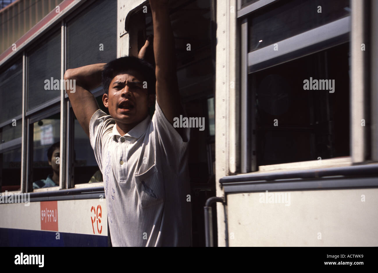 A bus conductor yells for passengers to get on board at a Yangon bus ...
