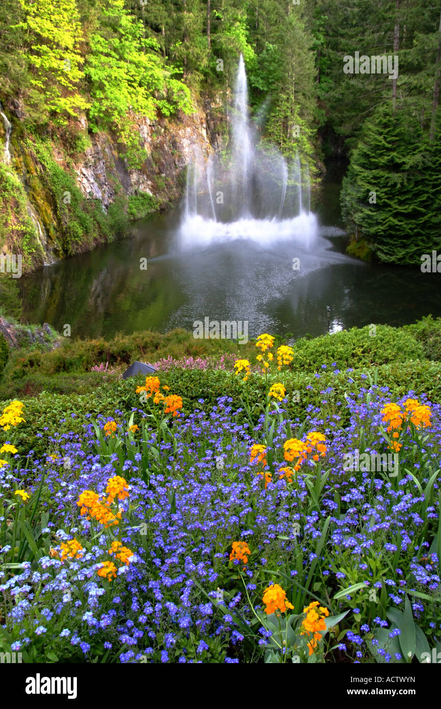 PORTRAIT VIEW OF WATER FALL FROM A FOUNTAIN WITH FLOWERS IN FORE FRONT ...