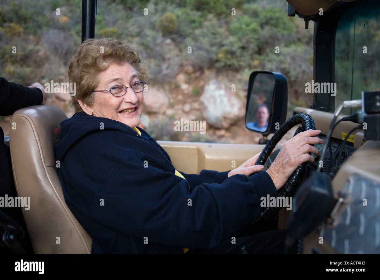 Amused woman at wheel of Hummer with driver reflected in side view ...