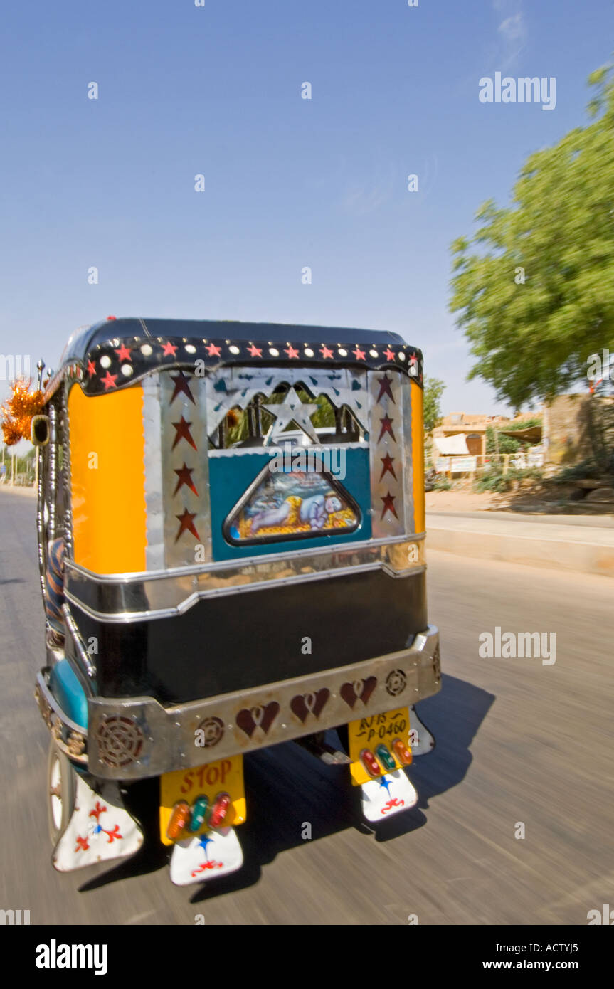 A decorated yellow and black auto rickshaw (tuk tuk) taken from another ...