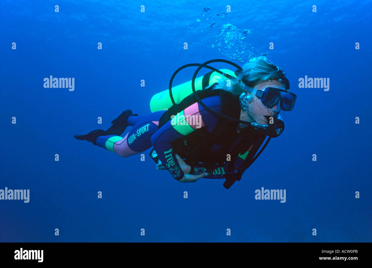 A female scuba diver finning underwater against a blue sea background ...