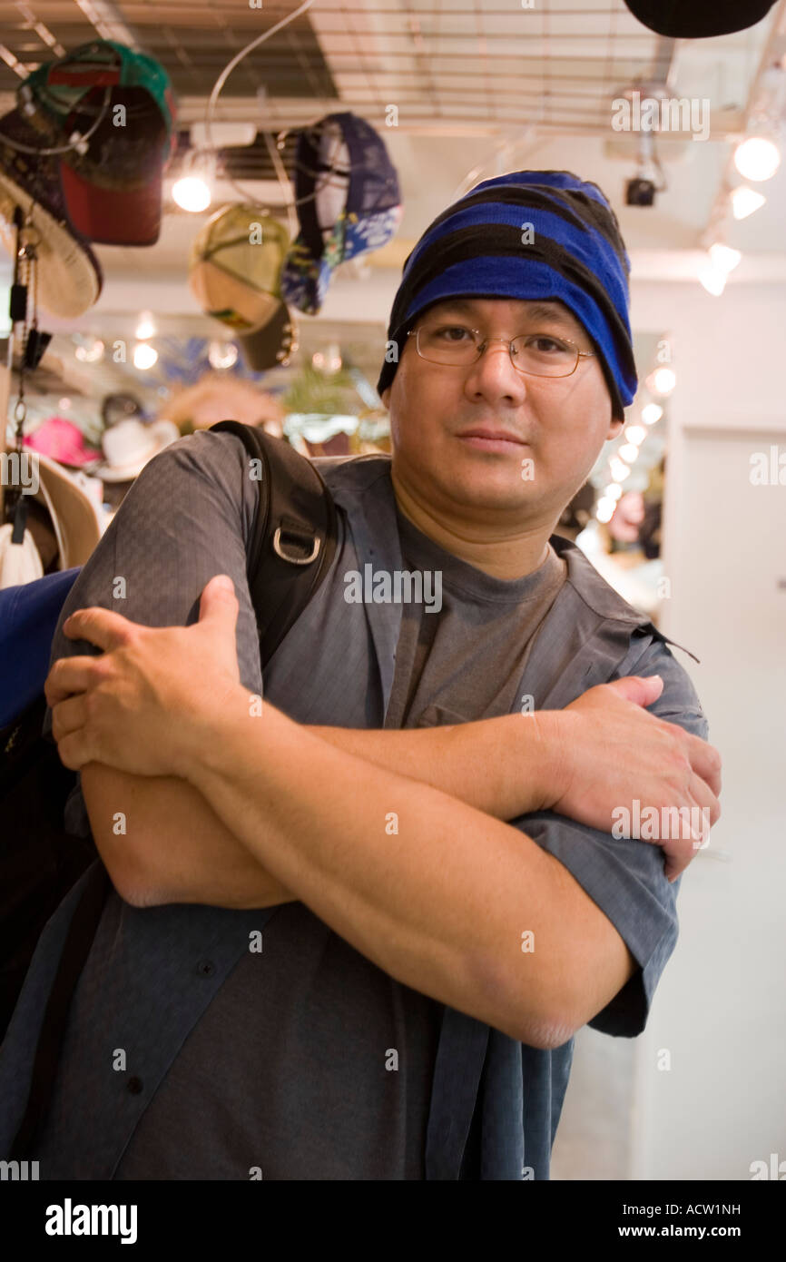 Chinese American man trying on a gangsta hat and crossing his arms ...