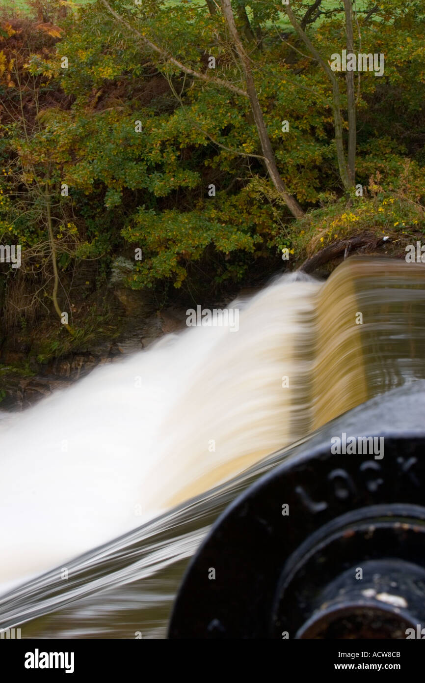 River irwell flowing fast over weir after heavy rain, at burrs country ...