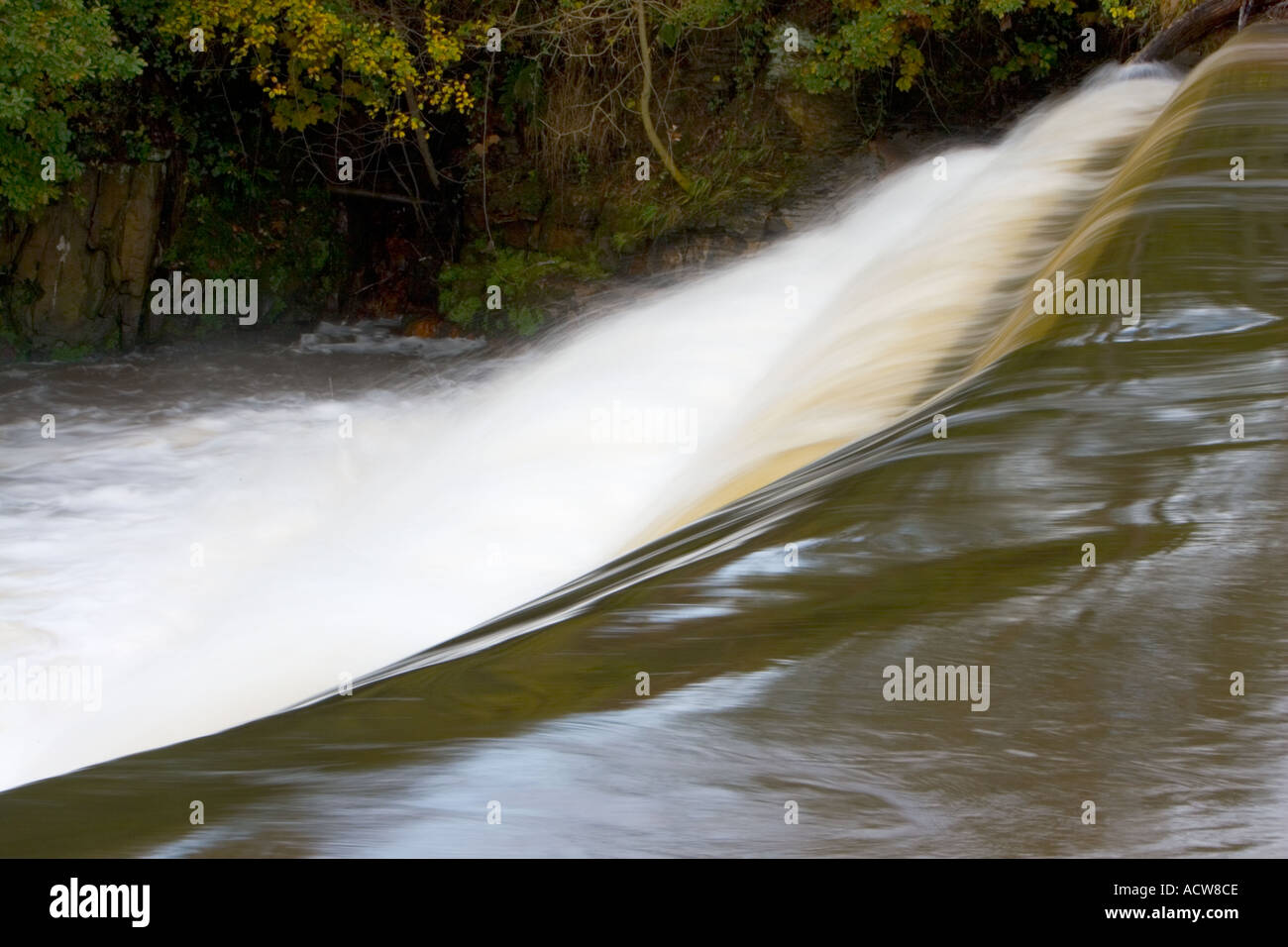River irwell flowing fast over weir after heavy rain, at burrs country ...