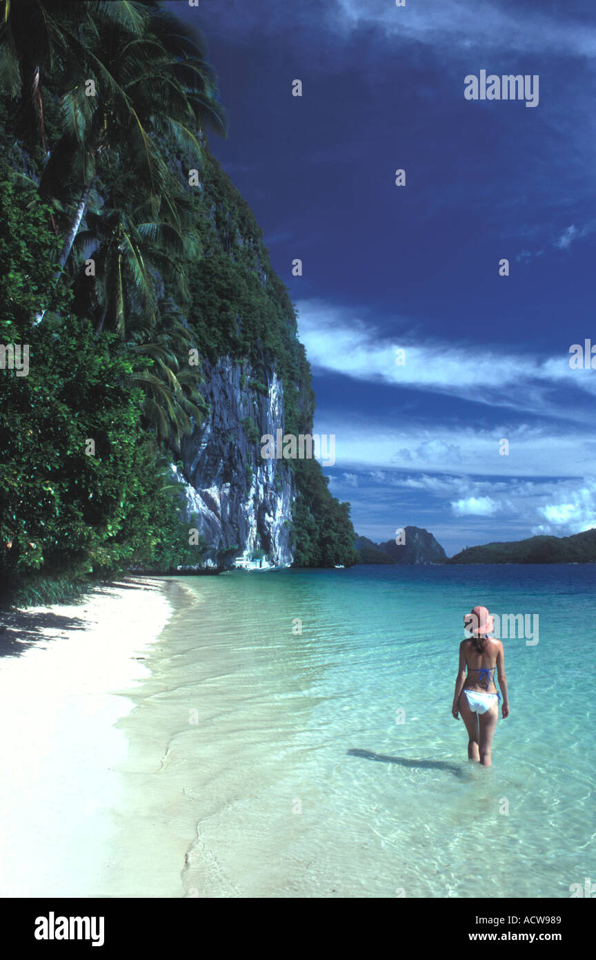 Philippines Palawan A tourist strolls through the tropical waters of ...