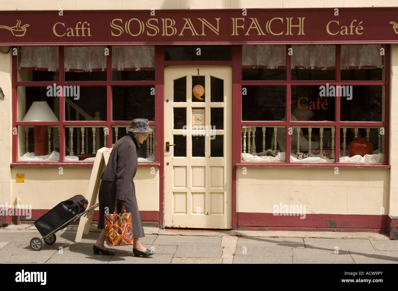 old woman walking past the Sosban Fach welsh cafe Lampeter Ceredigion ...