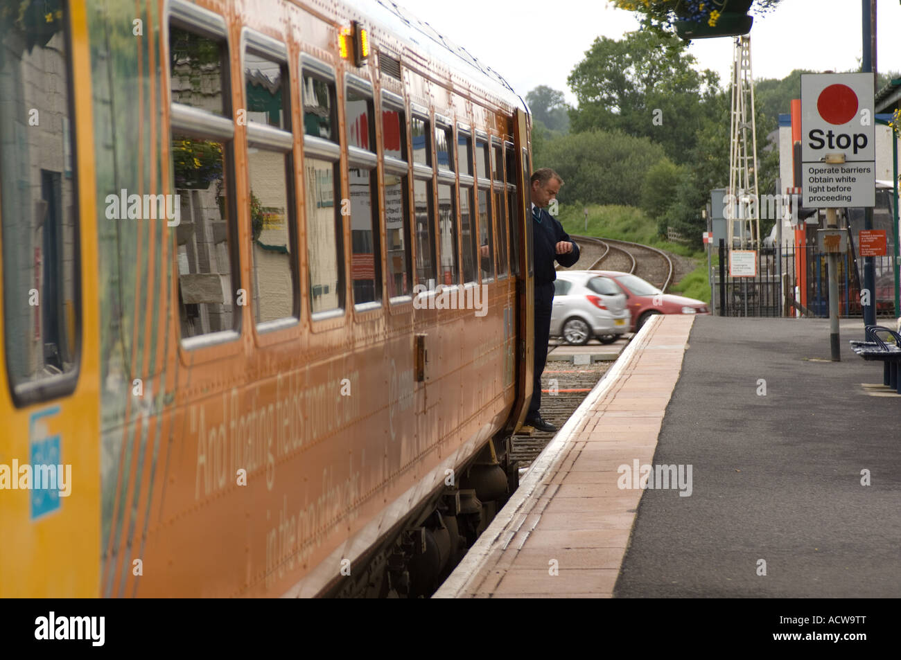 guard checking his watch on the train at station on the Heart of Wales ...