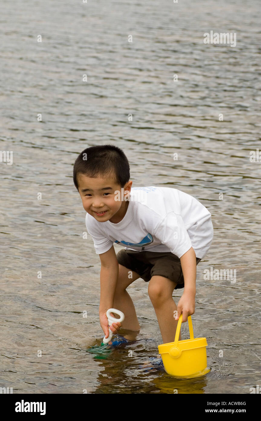 a boy readily using a bucket to splash sea water Stock Photo - Alamy