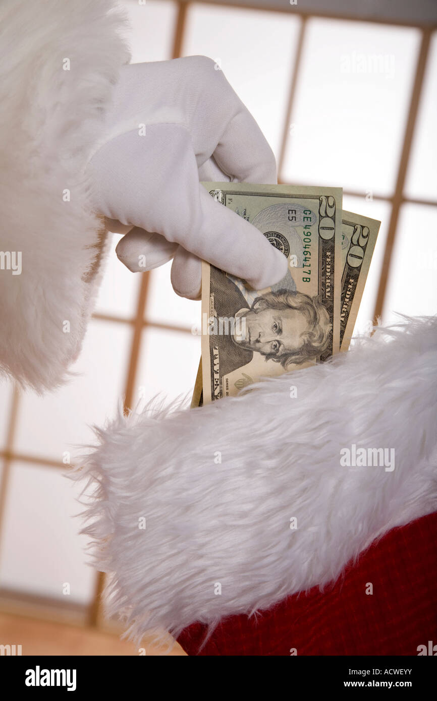 Santa putting money into stocking Stock Photo - Alamy