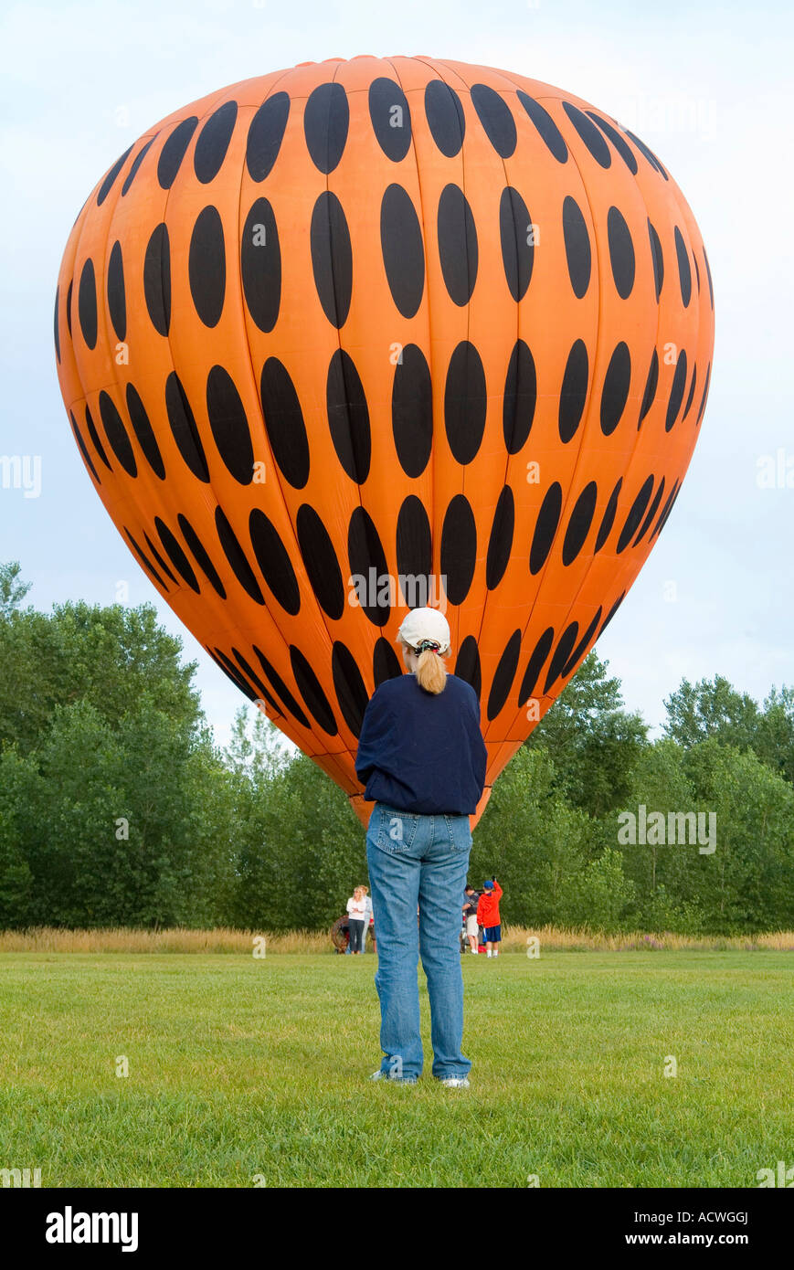 A WOMAN IS WATCHING AN HOT AIR BALLOON TAKING OFF THE GROUND Stock ...