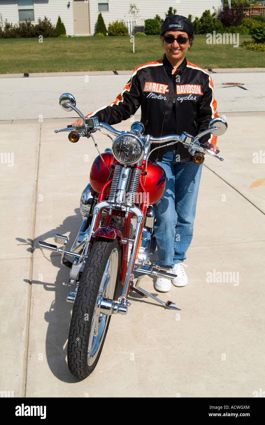 A HARLEY DAVIDSON RIDER GIRL IS STANDING BESIDE HER BIKE WHILE HOLDING ...