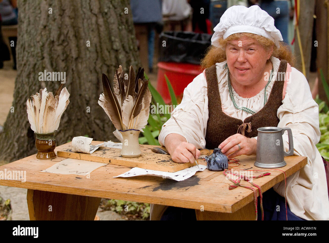 A WOMAN IN MEDIEVAL CLOTHES IS DOING PAINT WORK WITH FEATHER AND INK ...