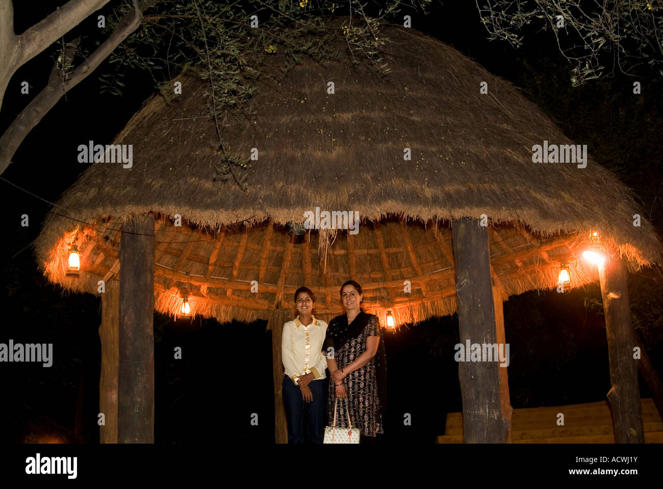 Two girls standing under a straw hut at night lighted by lanterns Stock ...