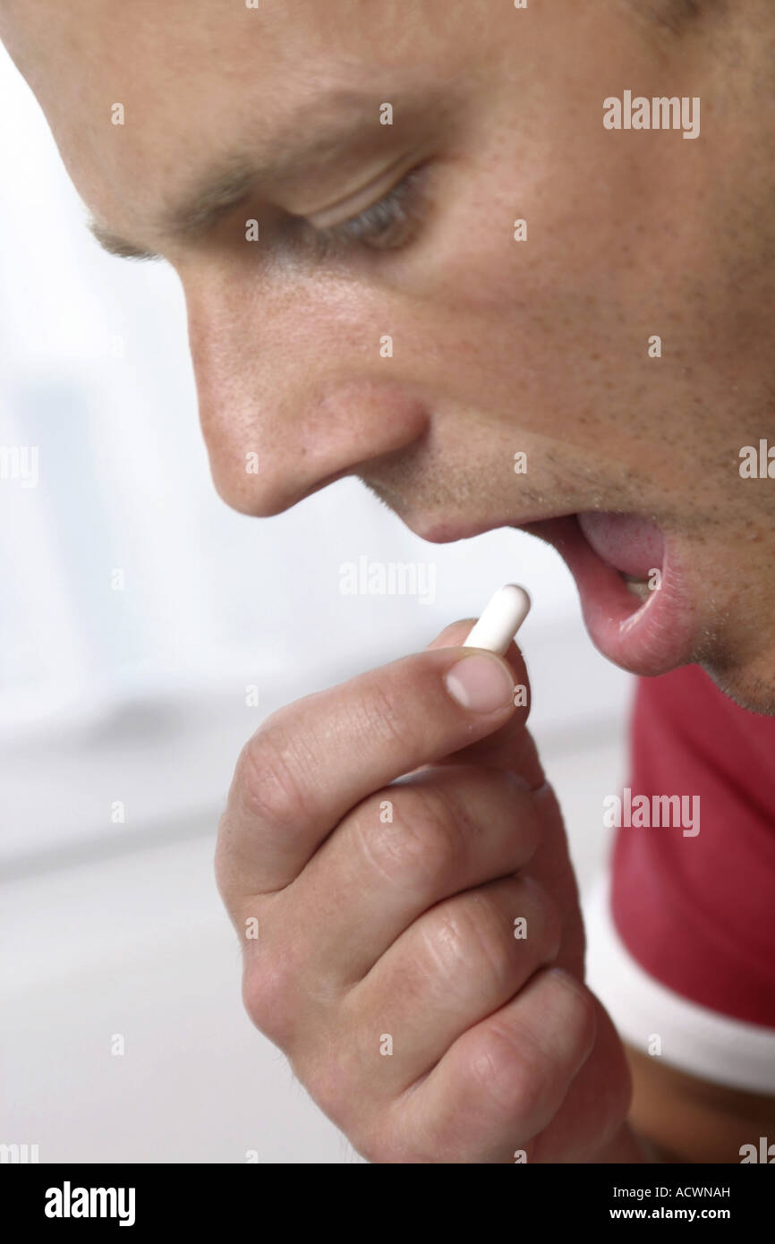 young man taking pills Stock Photo - Alamy