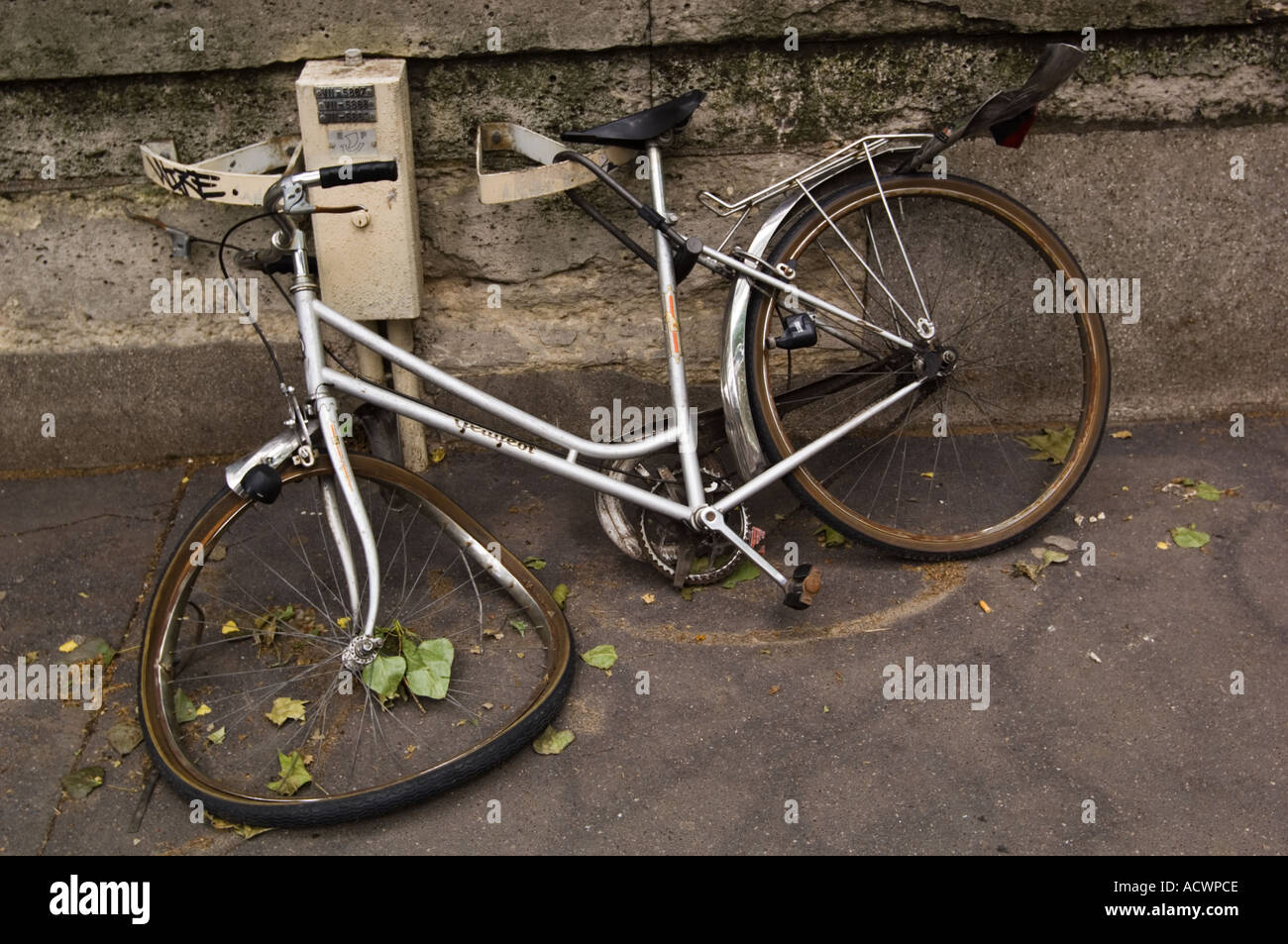 Color horizontal image of a damaged silver bicycle locked to a fixture ...