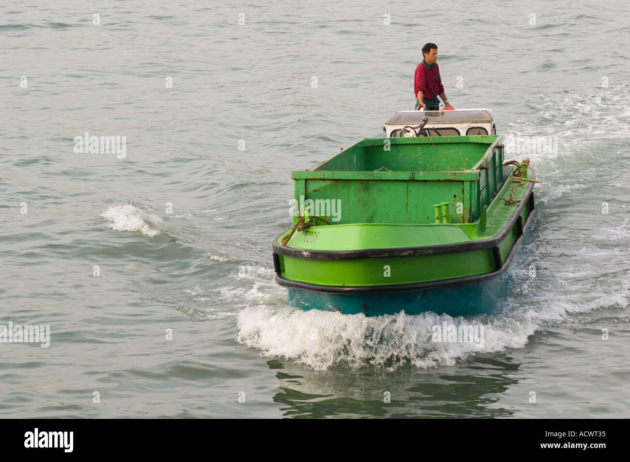 empty green garbage boat piloted on its way to work by an Italian trash ...
