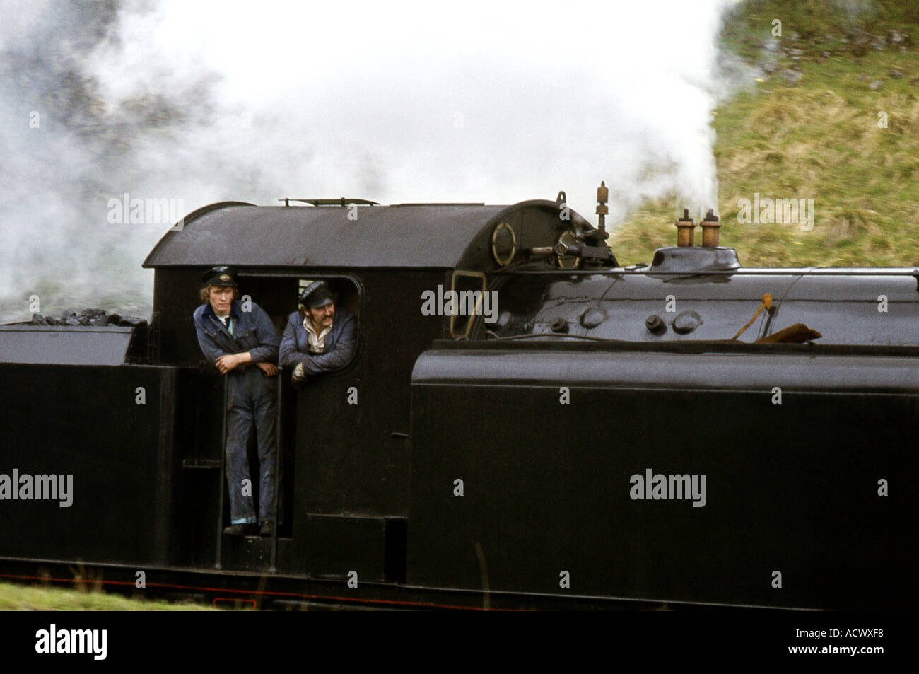 Two railway workers in the drivers cab of a saddle tank steam ...