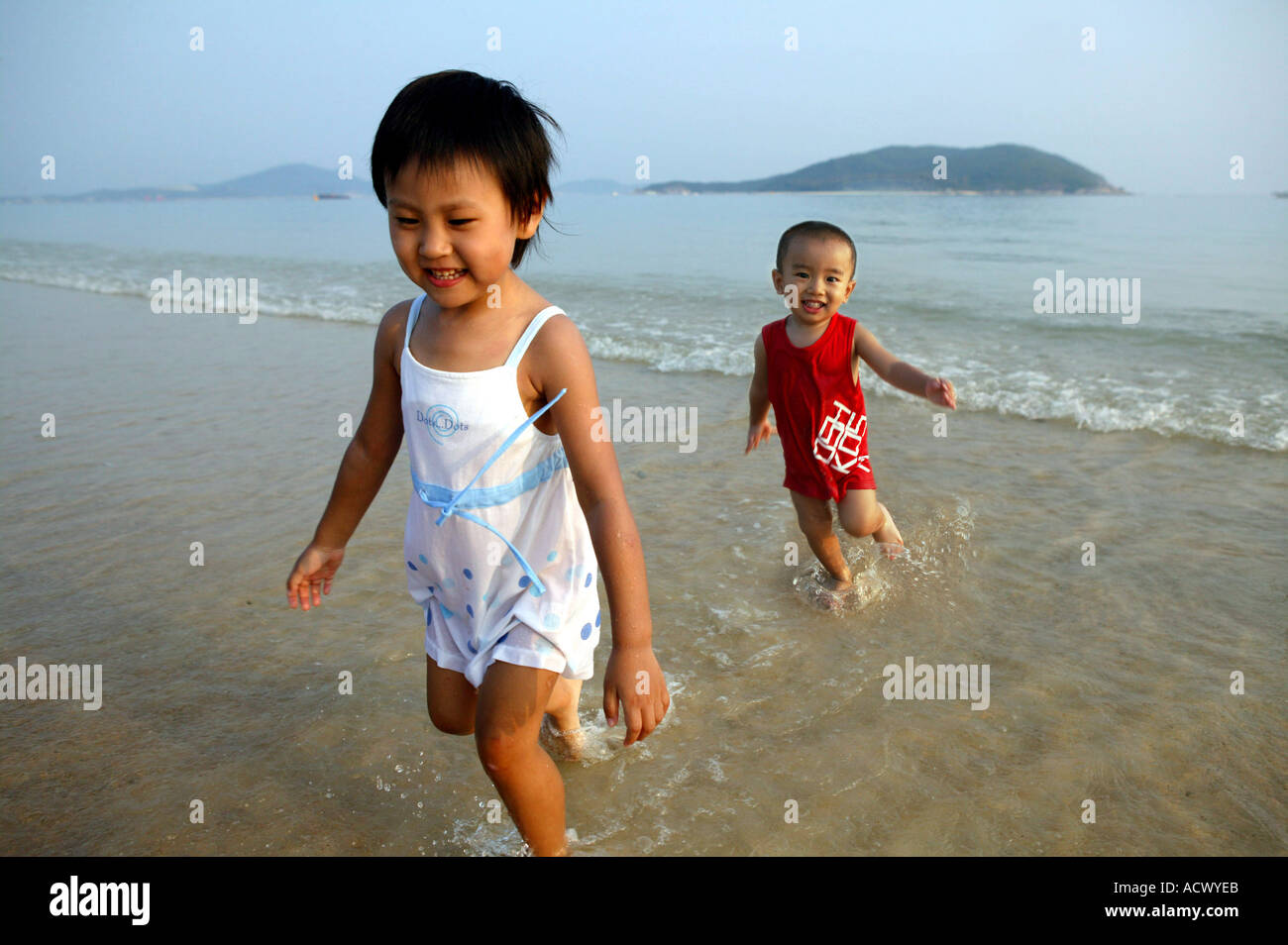 A chinese boy and a Chinese girl running together along the seaside ...