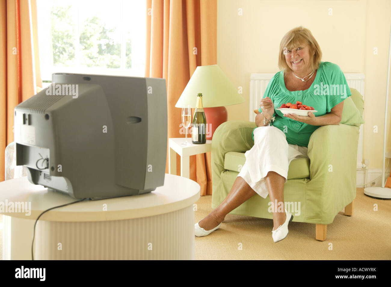 Lady watching television champagne strawberries hi-res stock ...