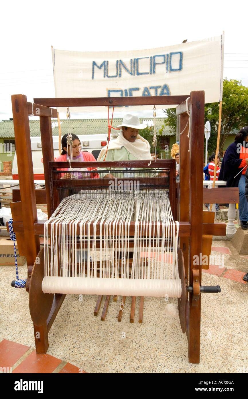 An artisan shows his work in progress using a manual loom for working ...