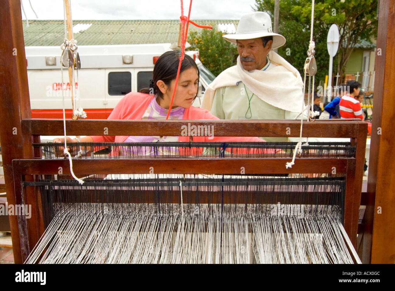 Two artisans show their work in progress using a manual loom for ...
