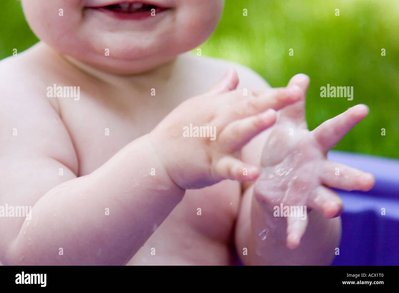Closeup of baby's clapping hands, with partial view of face showing ...
