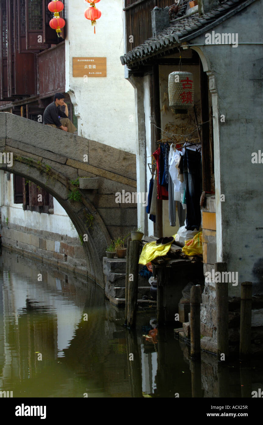 A young man sitting in contemplation on a bridge in Zhouzhuang, China ...