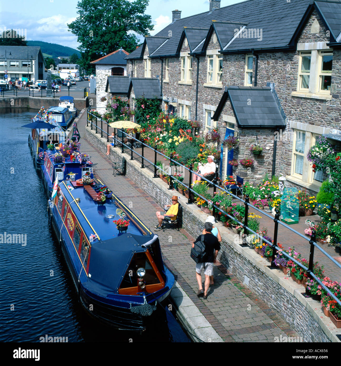 Boats moored by a row of terraced housing homes and people tourists ...