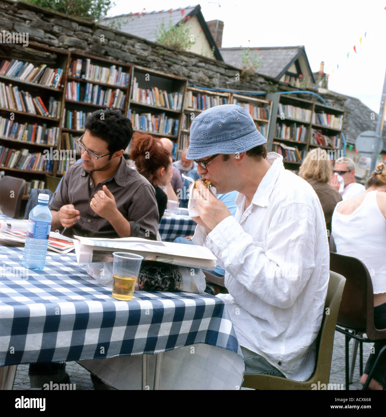 A young man eating by Honesty Bookshop book shelves at the outdoor ...