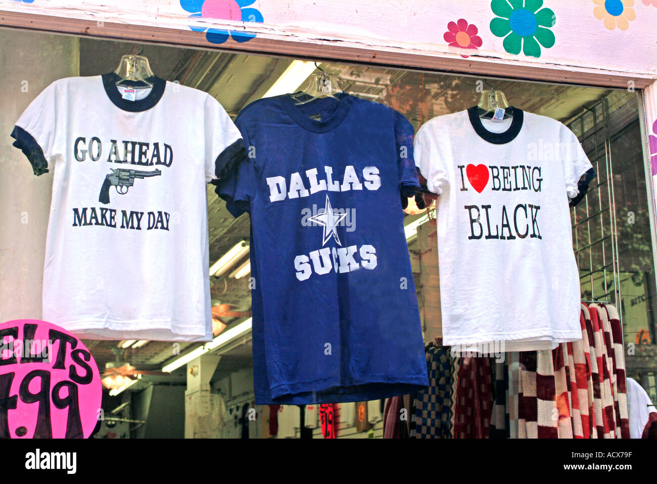 Mixed variety of t shirts with logos hanging in glass store front ...