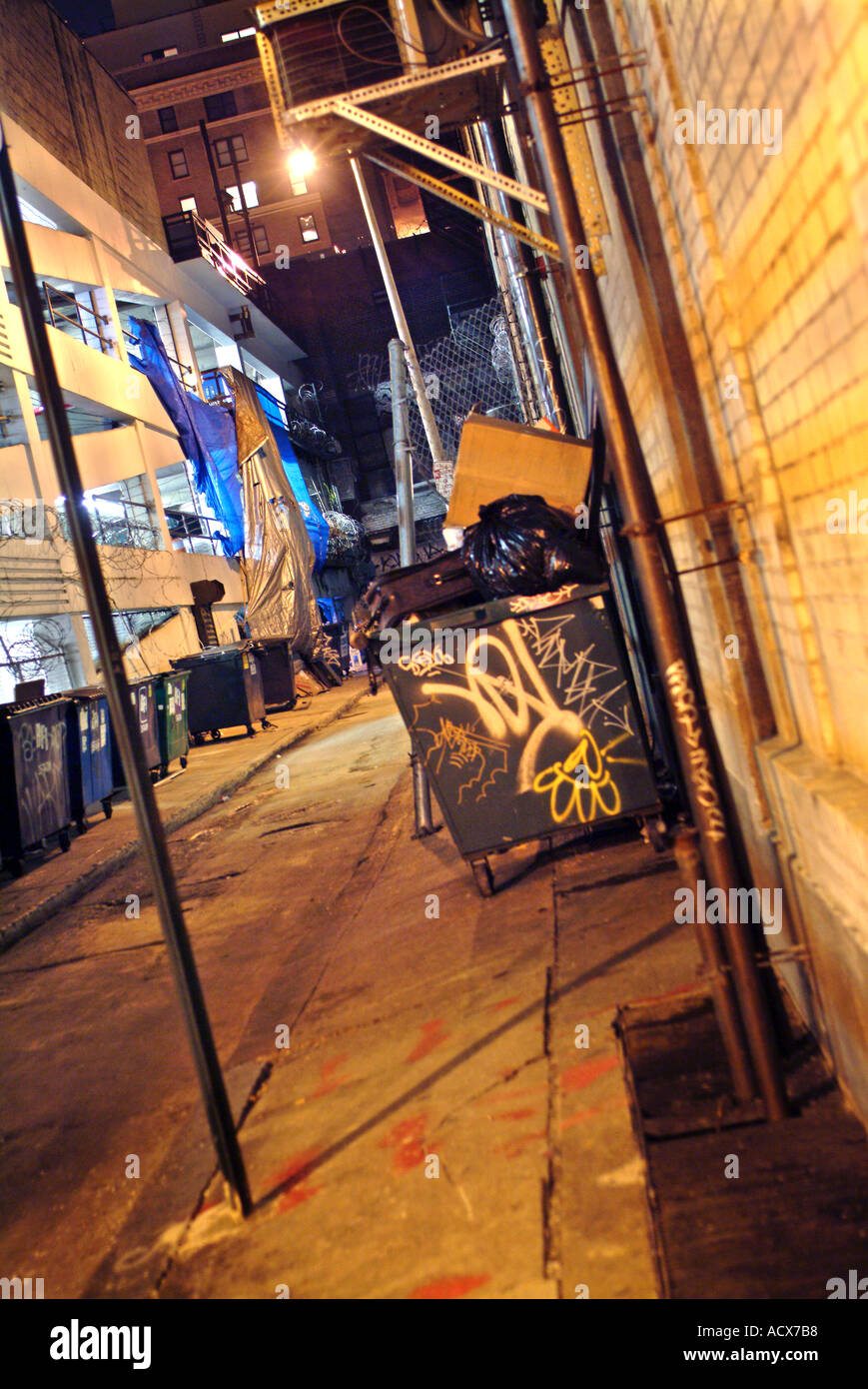 Dark alleyway at night with trash dumpsters and construction debris ...